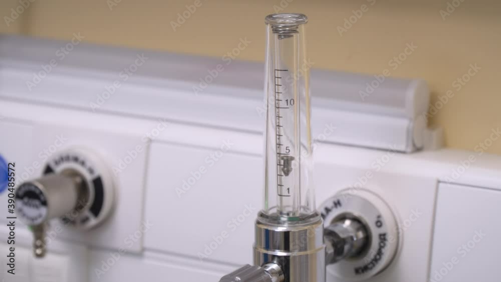 Close-up nurse hand adjusting medical oxygen. Flow Meter shows level ...