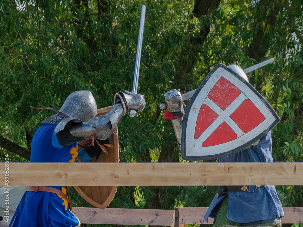 Two foot warriors in heavy medieval armor fight in the arena. Armed ...