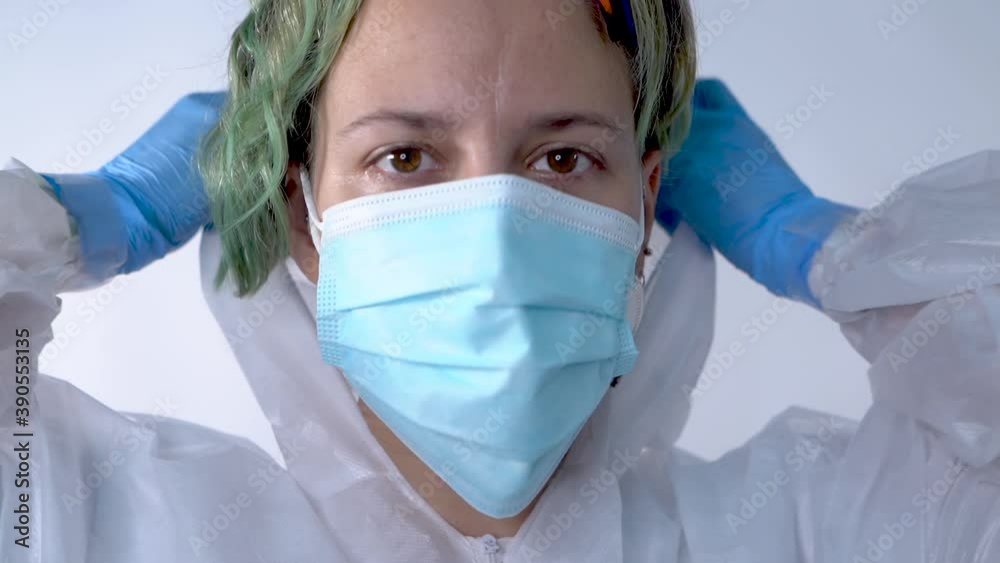 Young female doctor putting on the hood of her PPE suit to start ...