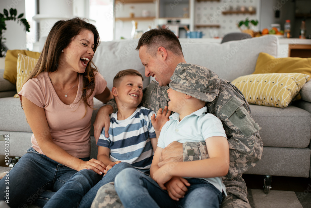 Happy soldier sitting on the floor with his family. Soldier and his ...
