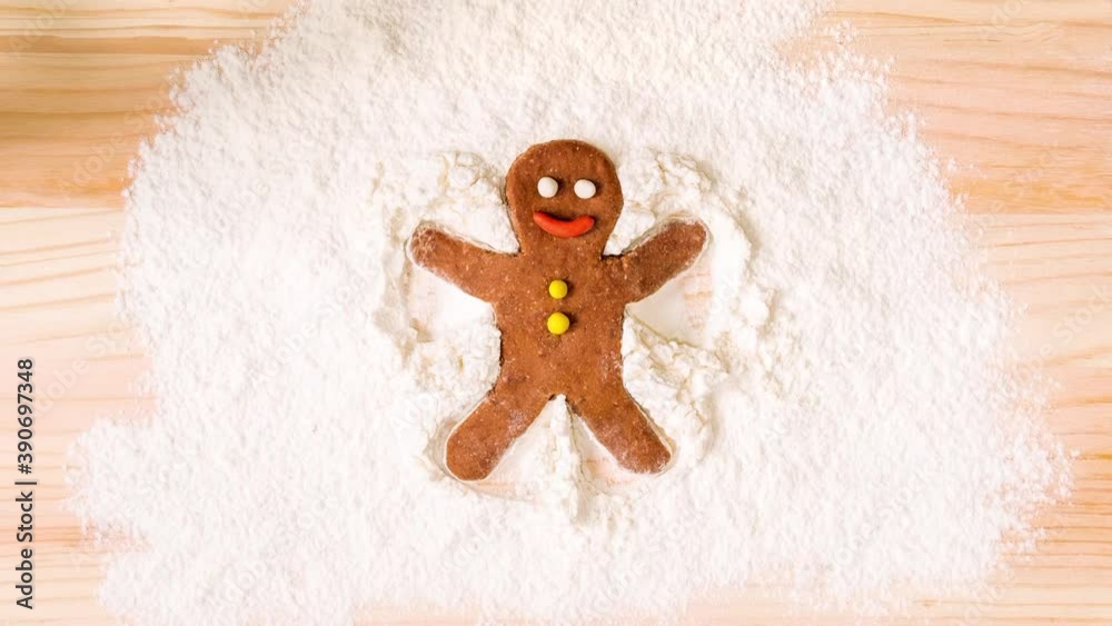 Stop motion animation of a gingerbread man making snow angel on flour ...