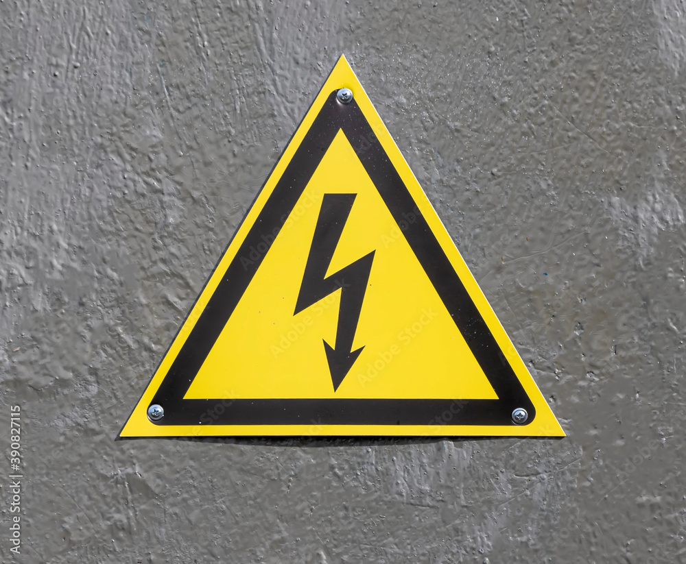 yellow triangle danger sign with lightning bolt on a gray wall ...