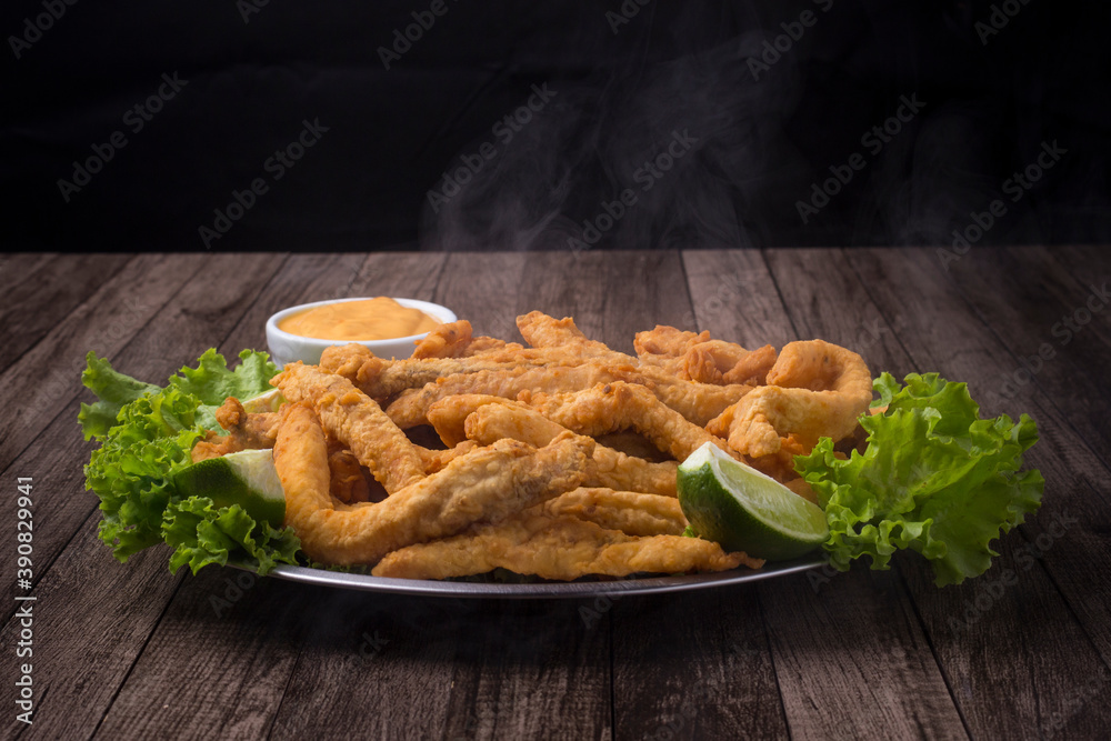 Breaded portion and fried fish served on lettuce leaves with lemons and ...