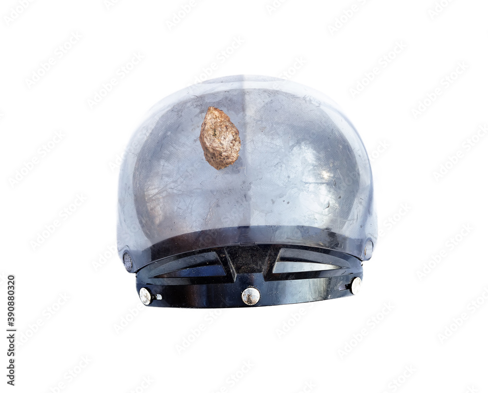 Helmet pierced by a stone on white background. Safety and road ...