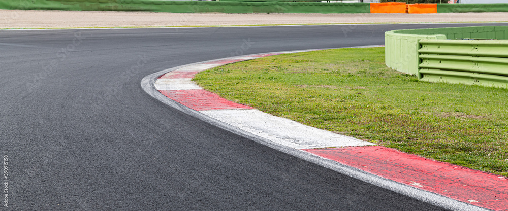 Rough curb on asphalt right turn motor sport track with green field ...