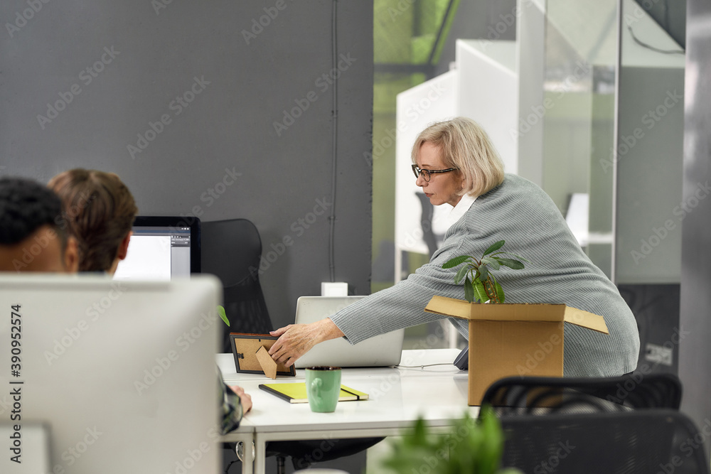 New employee aged woman, senior female intern putting picture frame on ...