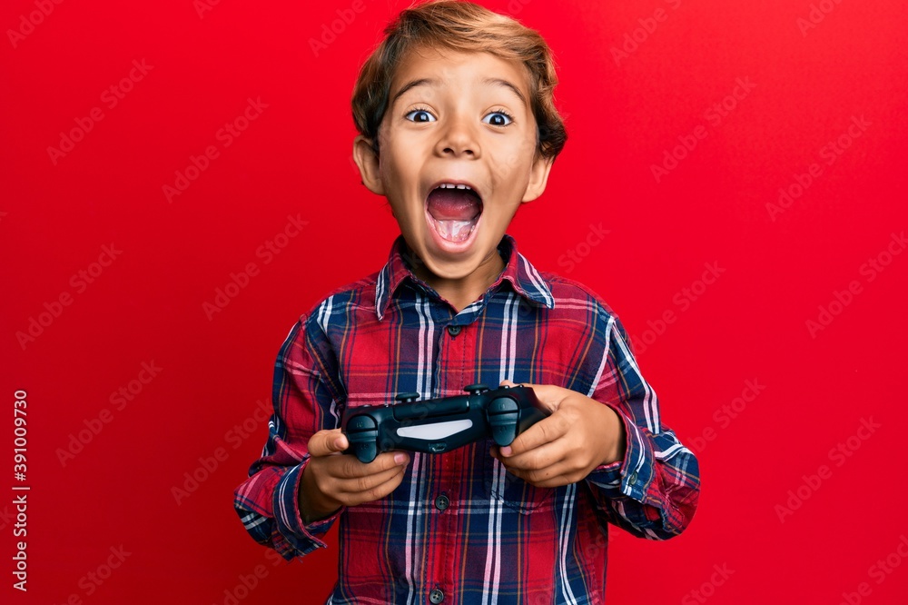 Foto de Adorable latin kid playing video game holding controller ...