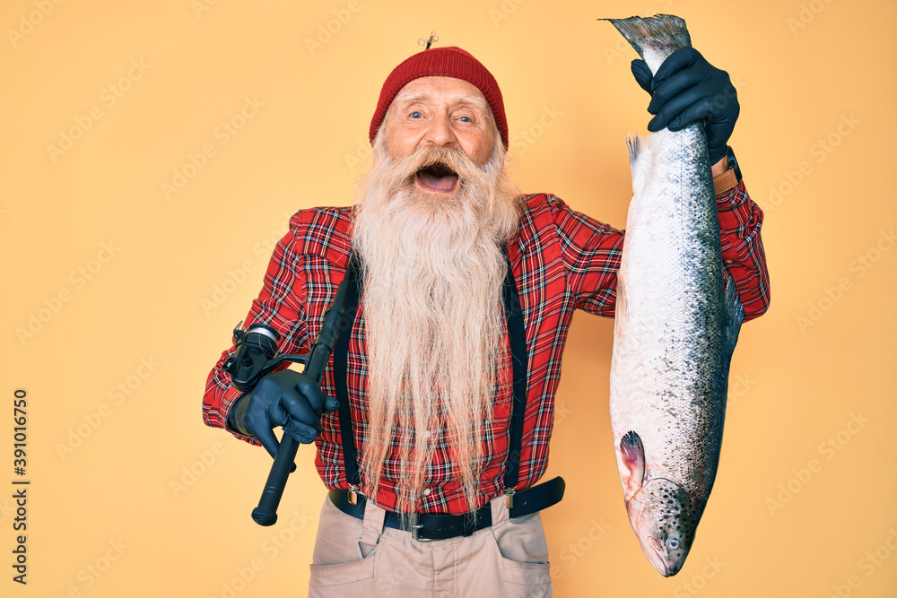 Old senior man with grey hair and long beard holding fishing rod and ...
