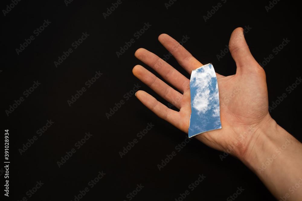 Holding blank broken mirror splinter in palm of hand against black ...