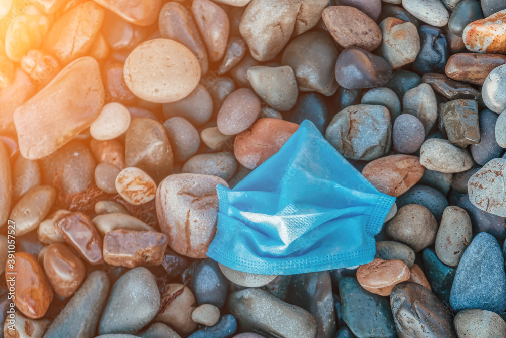 Close-up used Face mask on pebble beach, have started polluting water ...