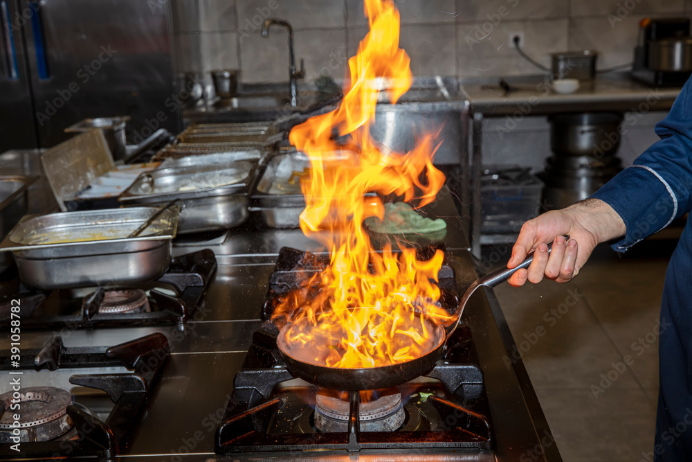 Foto de Flame in the pan. Professional Chef makes flambe for food in ...