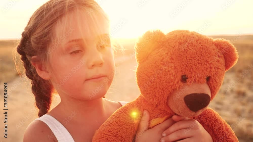 little kid girl hugging a teddy bear toy portrait in the park in nature ...
