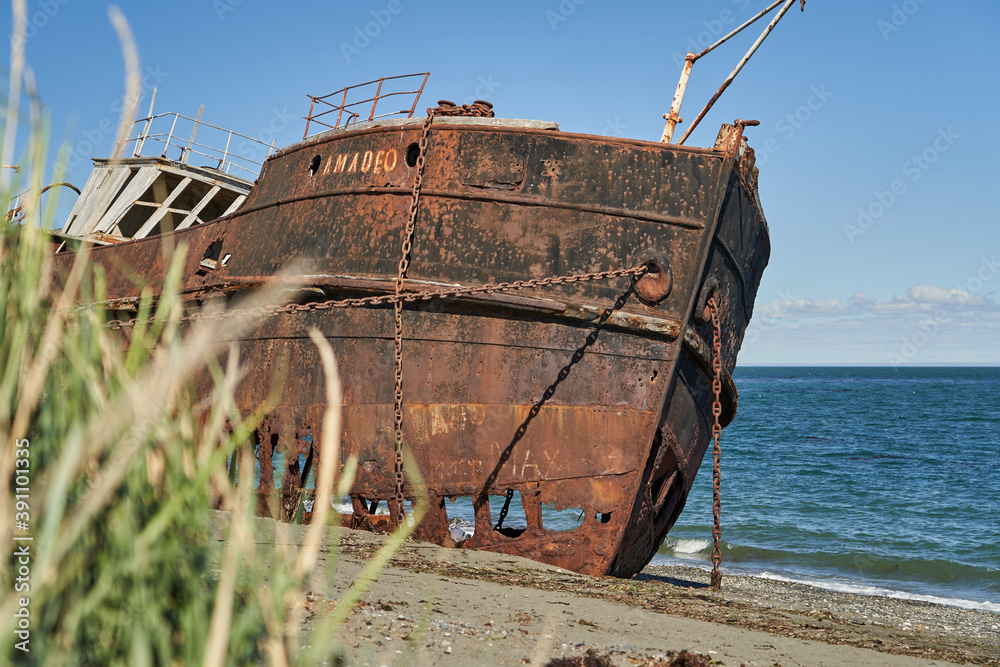 old rusty and rotten ship wreck with holes in its carcass, lying behind ...