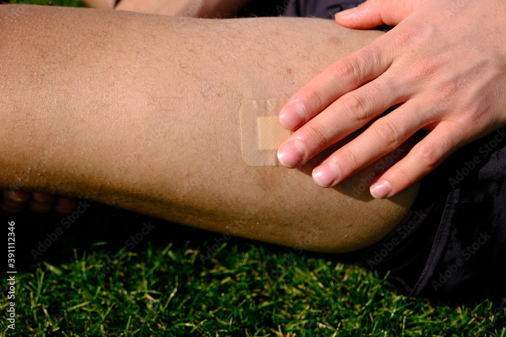 apply a plaster to the wound on the leg. wound care. first aid after a ...