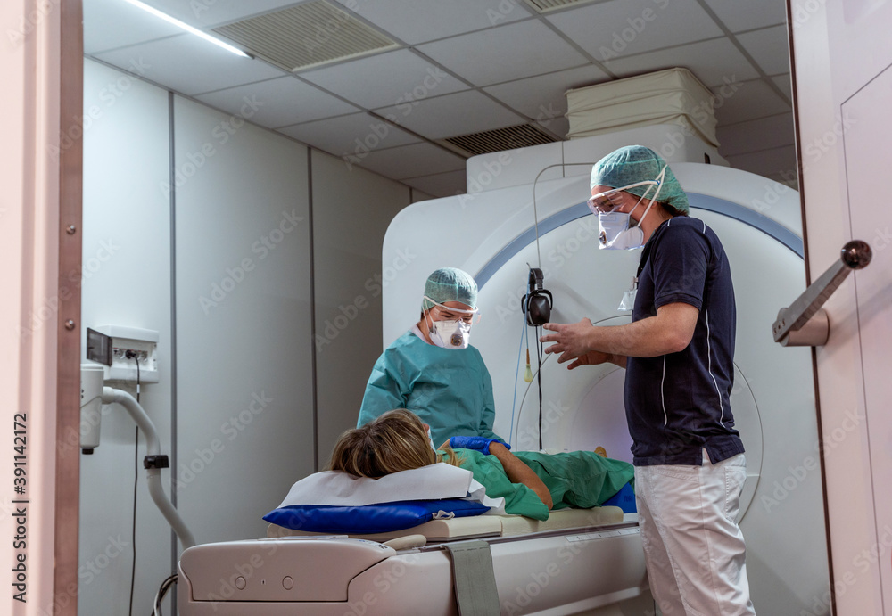 Female patient having CT scan examination while radiologist is ...