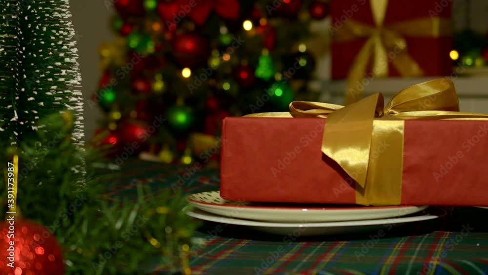 4K. a Christmas gift in a red wrapper and yellow ribbon is taken from a ...