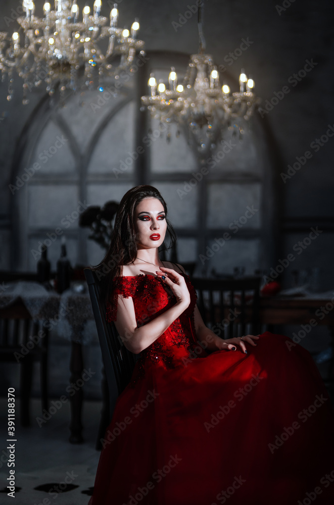 Bloodthirsty female vampire in red dress. Medieval interior Stock Photo ...