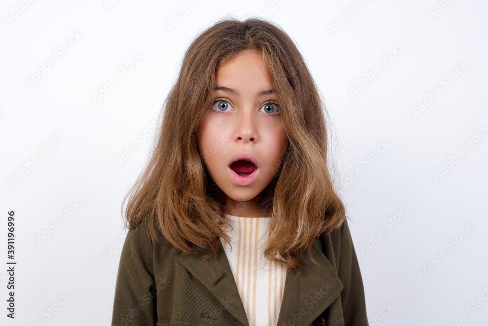 Beautiful little girl standing against white background, having stunned ...