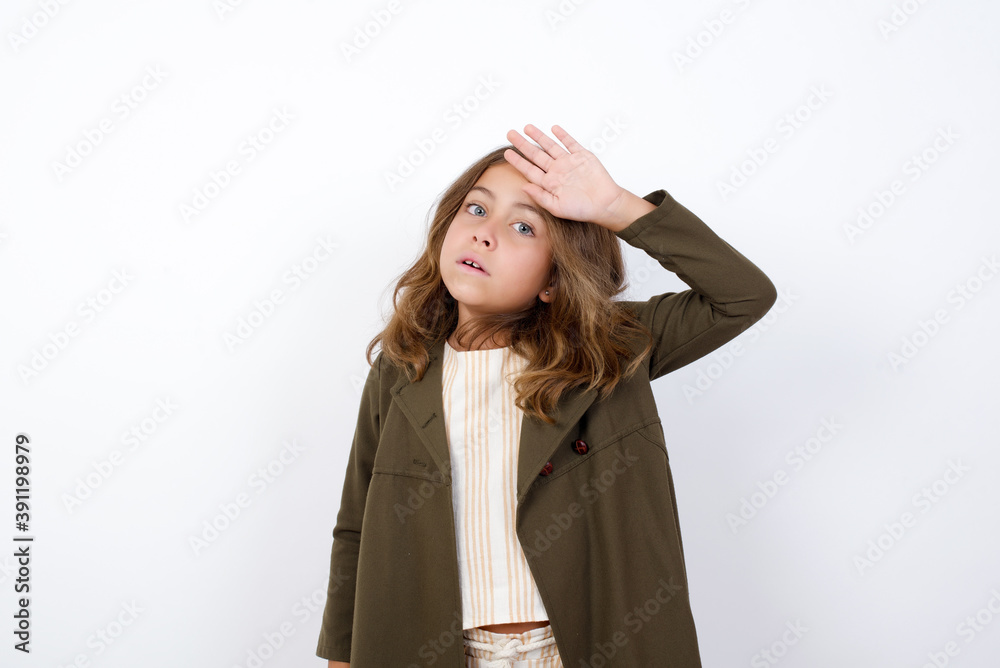 Beautiful little girl standing against white background, wiping ...