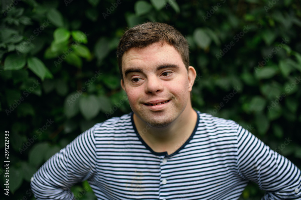 Portrait of down syndrome adult man standing outdoors at green ...