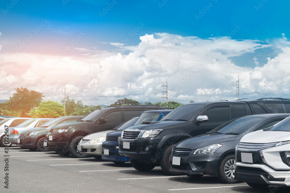 Cars parking in asphalt parking lot in a row with blue sky background. Outdoor parking lot with ...