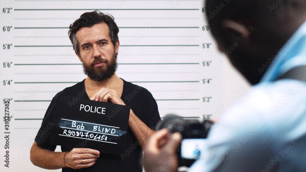 Criminal stand on measuring scale background in police station posing ...