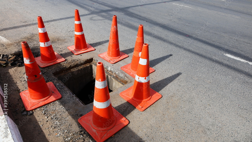 Traffic cones around the manhole open.Orange plastic cones on the ...