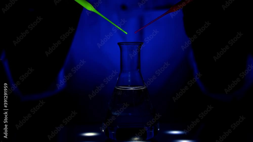 A scientist is mixing a red and green color solution on a magnetic ...