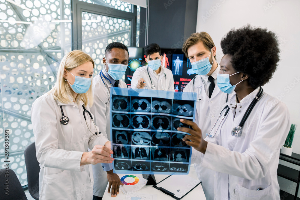 Multiethnical five doctors, wearing lab coats and medical masks ...