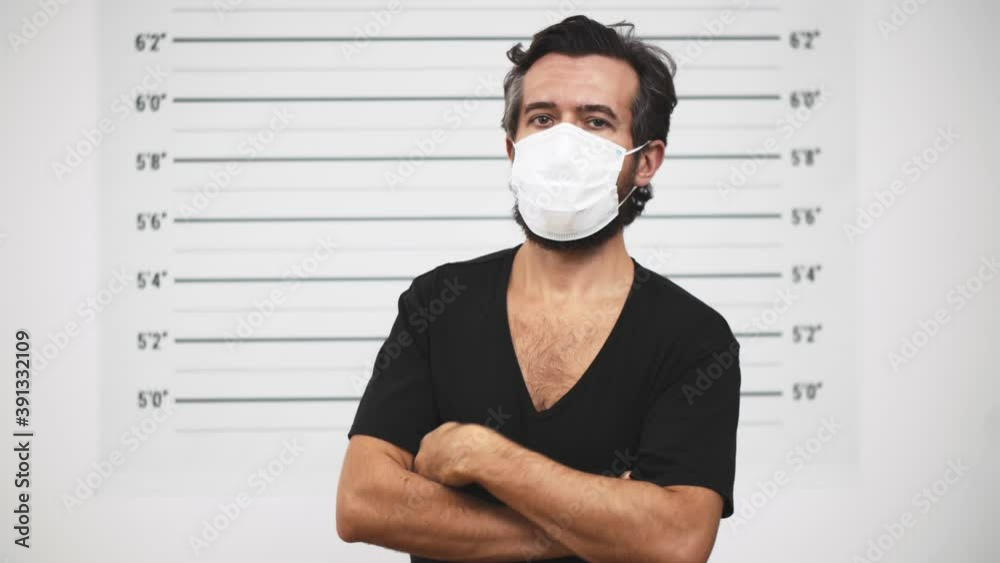 Mugshot of a serious bearded man removing safety mask at police station ...