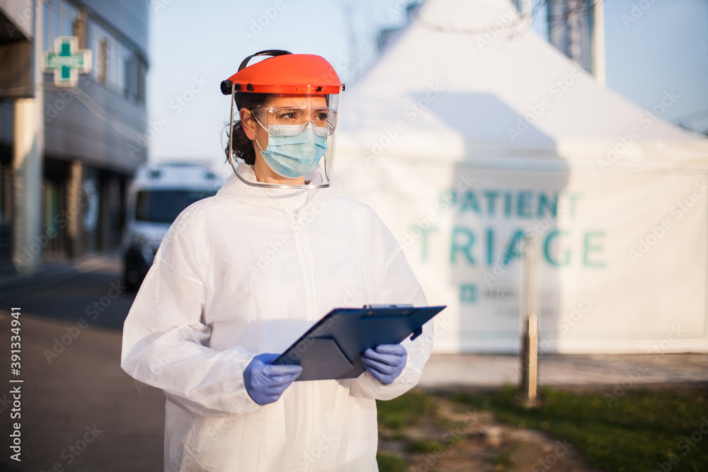 Paramedic wearing personal protective equipment PPE holding folder ...