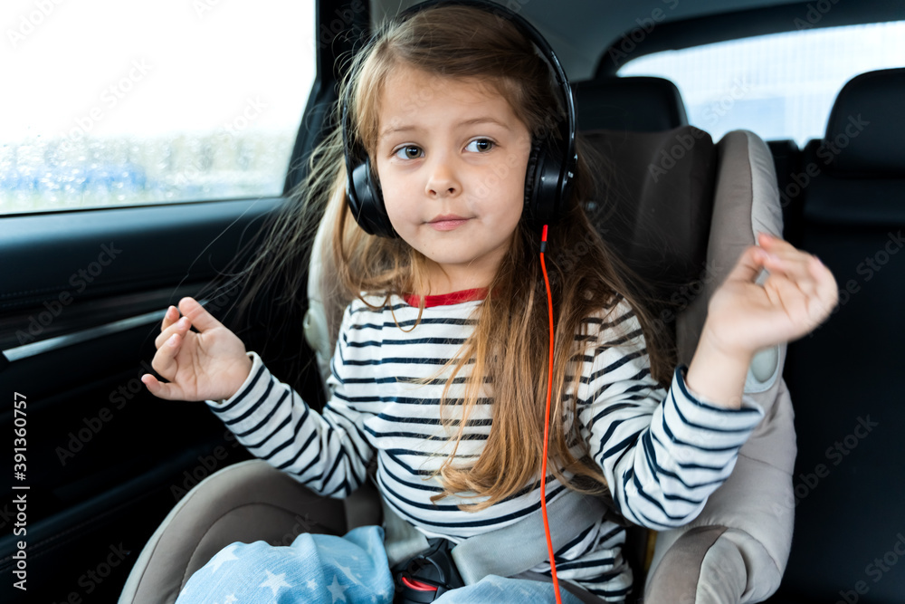 Little cute caucasian girl is driving in car.Kid listening to music ...