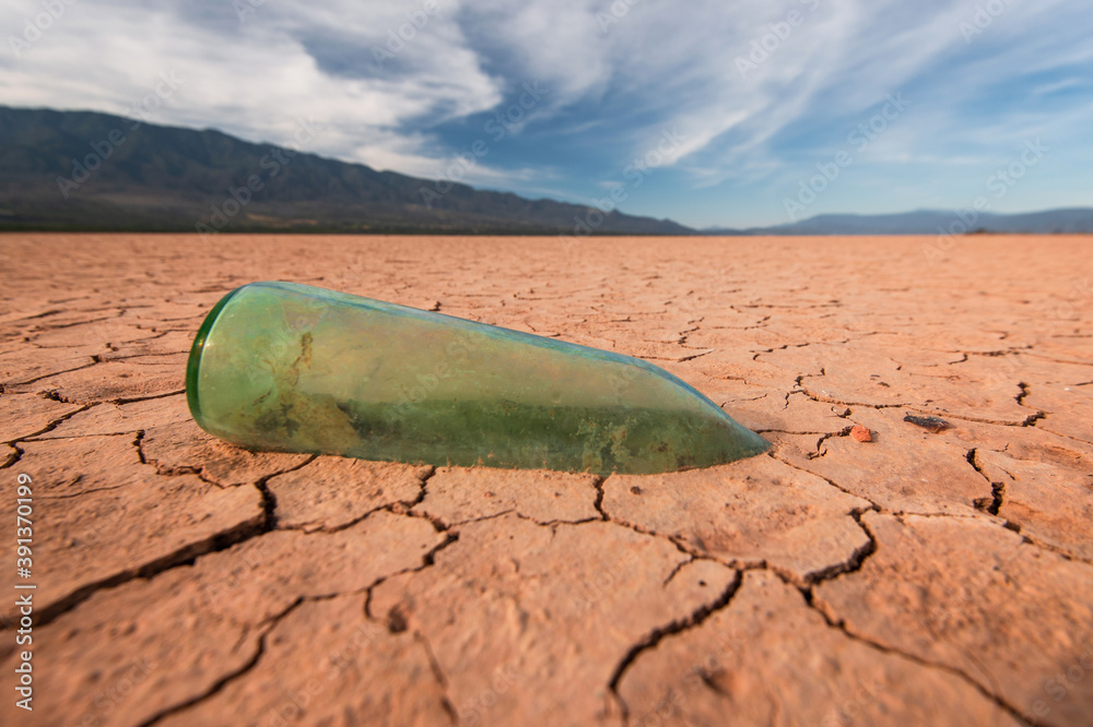 Foto de aged glass bottle stuck in the mud as a symbol of drought do ...