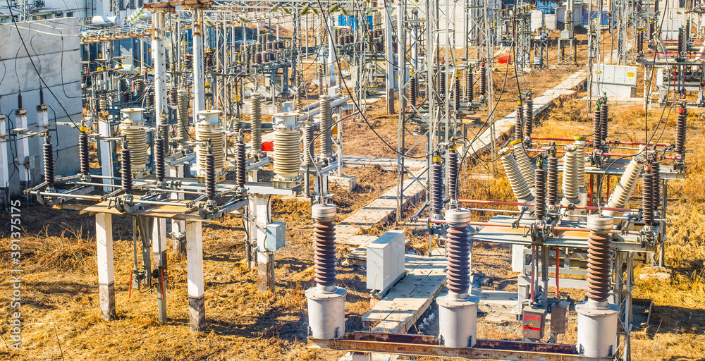 industrial background of high voltage substation on yellow dry grass ...