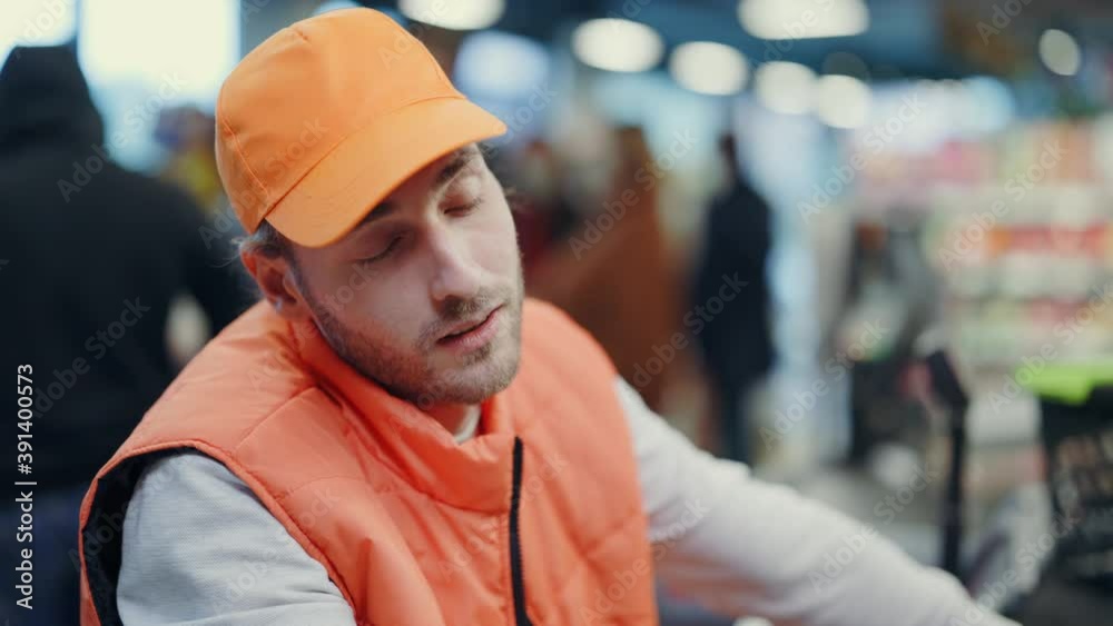 Bearded baffoled young male cashier arguing with customer shaking head ...