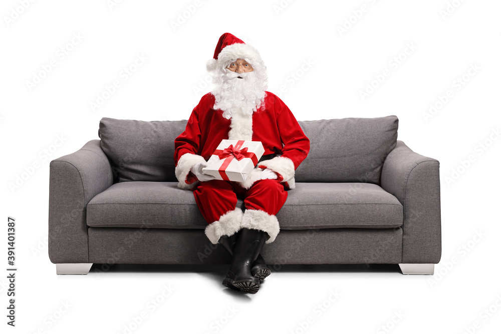 Full length portrait of a santa claus sitting on sofa and holding a ...
