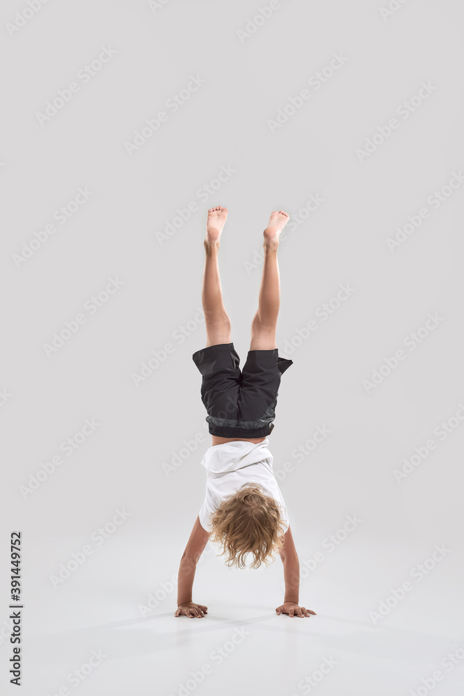 Full length shot of little playful boy child standing on his arms with ...