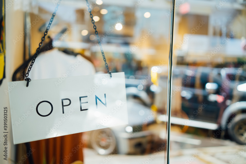 open sign welcoming customers hanging on glass door , in front of ...