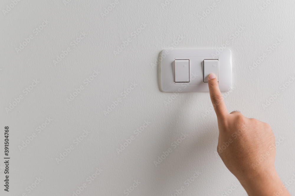 Foto de Earth Hour, Close up male hand turn off the light to saving ...