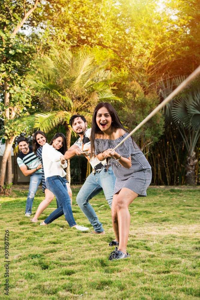 Indian asian young friends playing tug of war or rassi khech outdoors ...