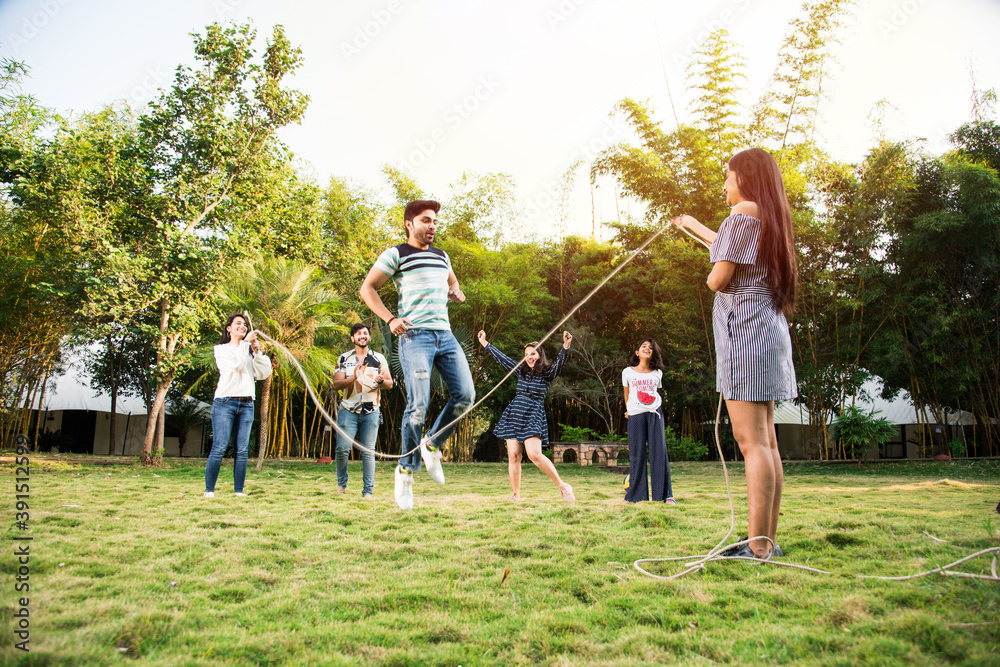 Indian asian young friends playing jumping rope, enjoying recreational ...