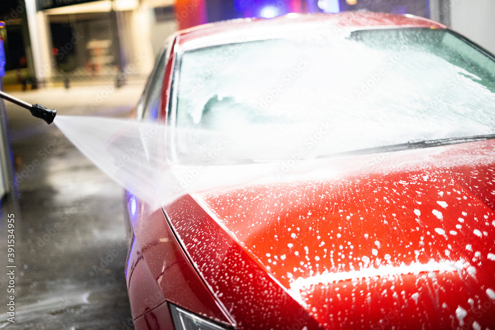 Person washing a red car with high pressure water in a car wash. Stock ...