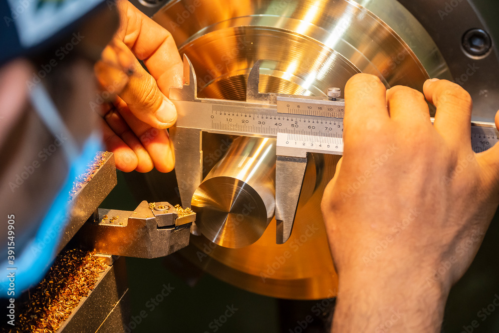 The machine operator measure the dimension of brass shaft by Vernier ...
