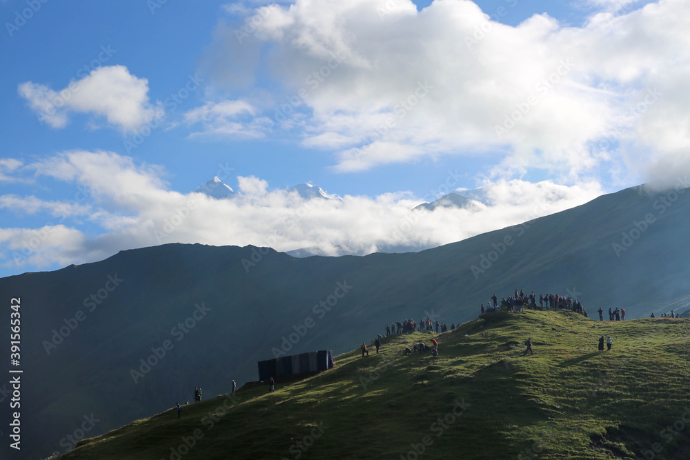 Himalayan landscape with cloud, people and meadows. The Himalayan range ...