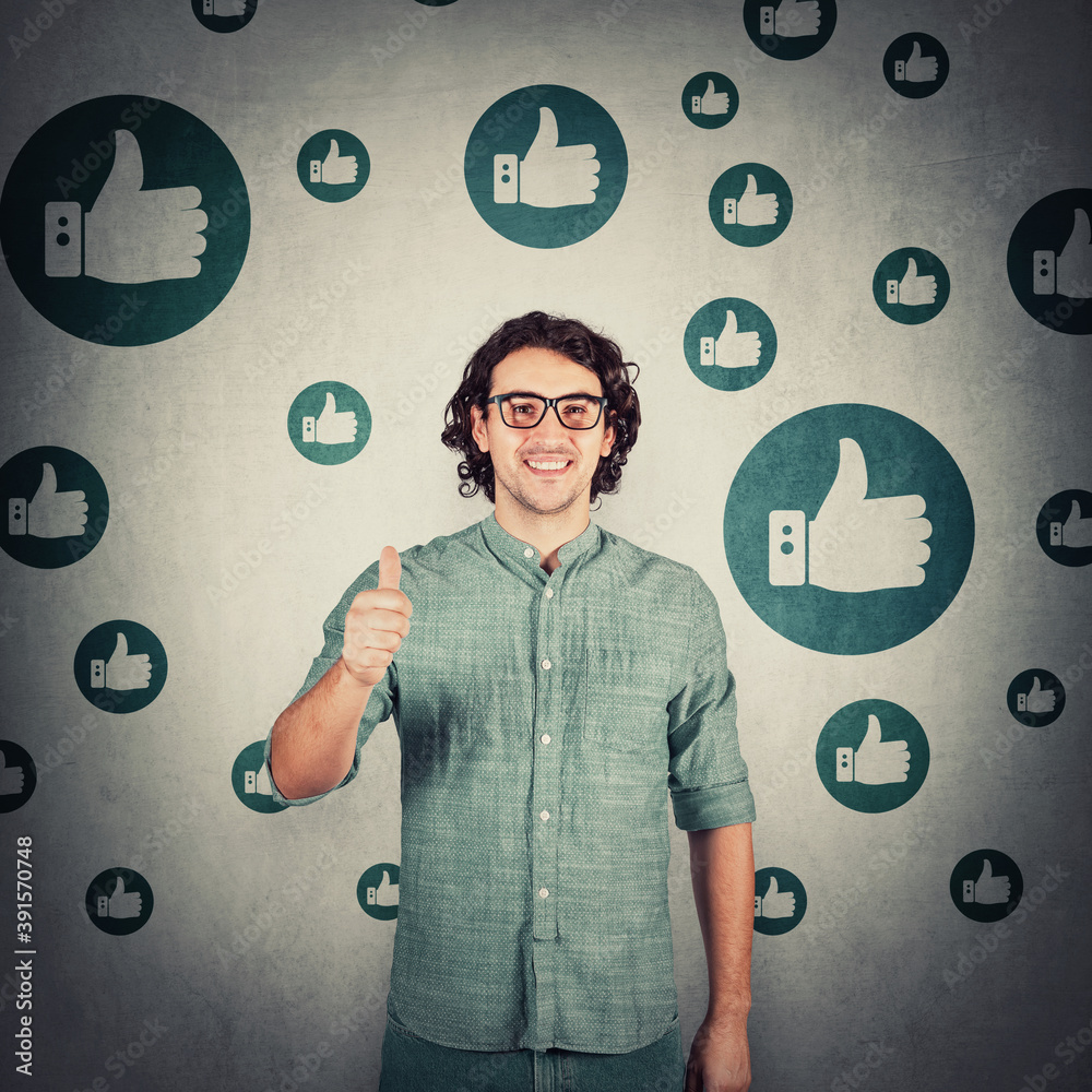 Contented male shows thumbs up positive gesture, looking to camera ...