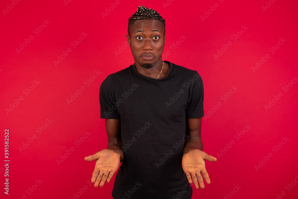 Confused Young African American handsome man standing against red ...