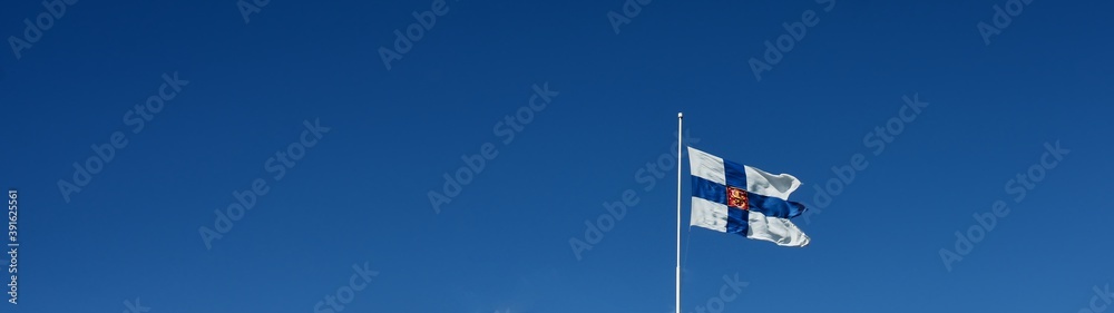 Finland state flag with national coat of arms against clear blue sky ...