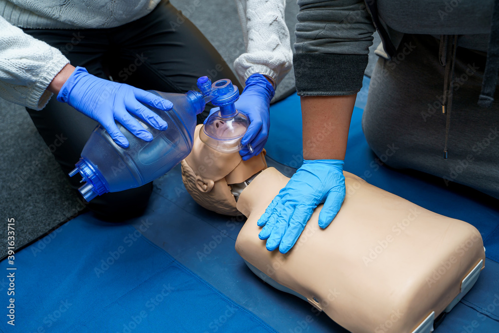 Man using CPR technique on dummy in first aid class. Oxigen mask on ...