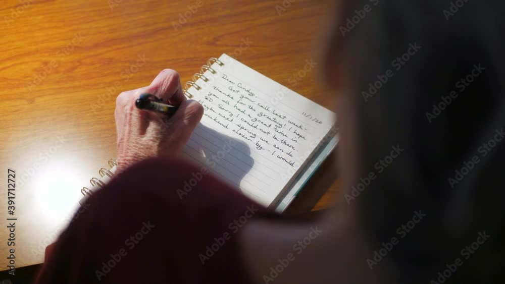 An old caucasian woman with aging hands writing an old fashioned mail ...