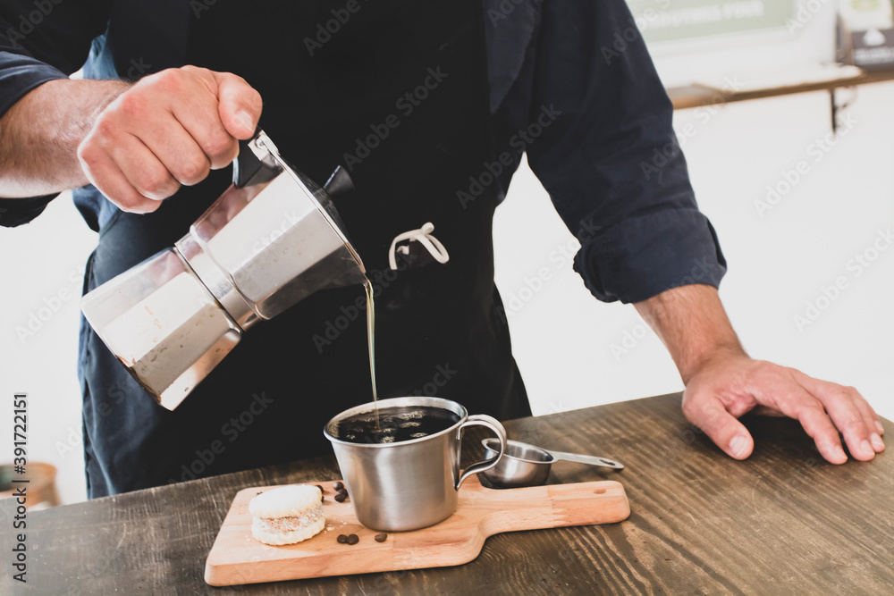 Male Barista preparing fresh espresso in coffee maker for customer in a ...